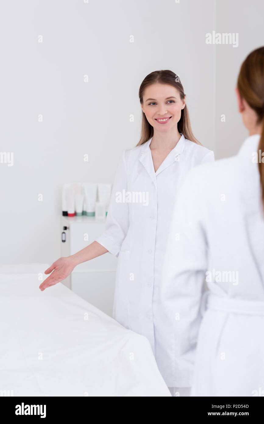 smiling cosmetologist in white coat and client in salon Stock Photo - Alamy