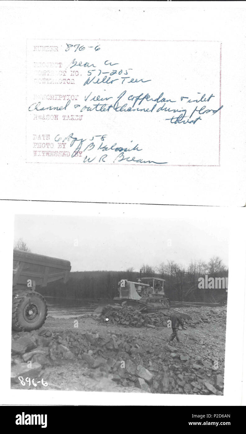 . English: A bulldozer builds up the levee while a worker watches ...