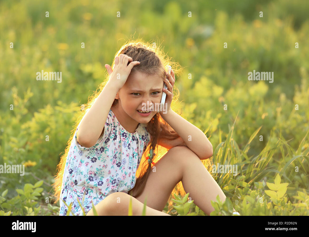 Angry serious cute kid girl sitting on the glass, talking on mobile ...
