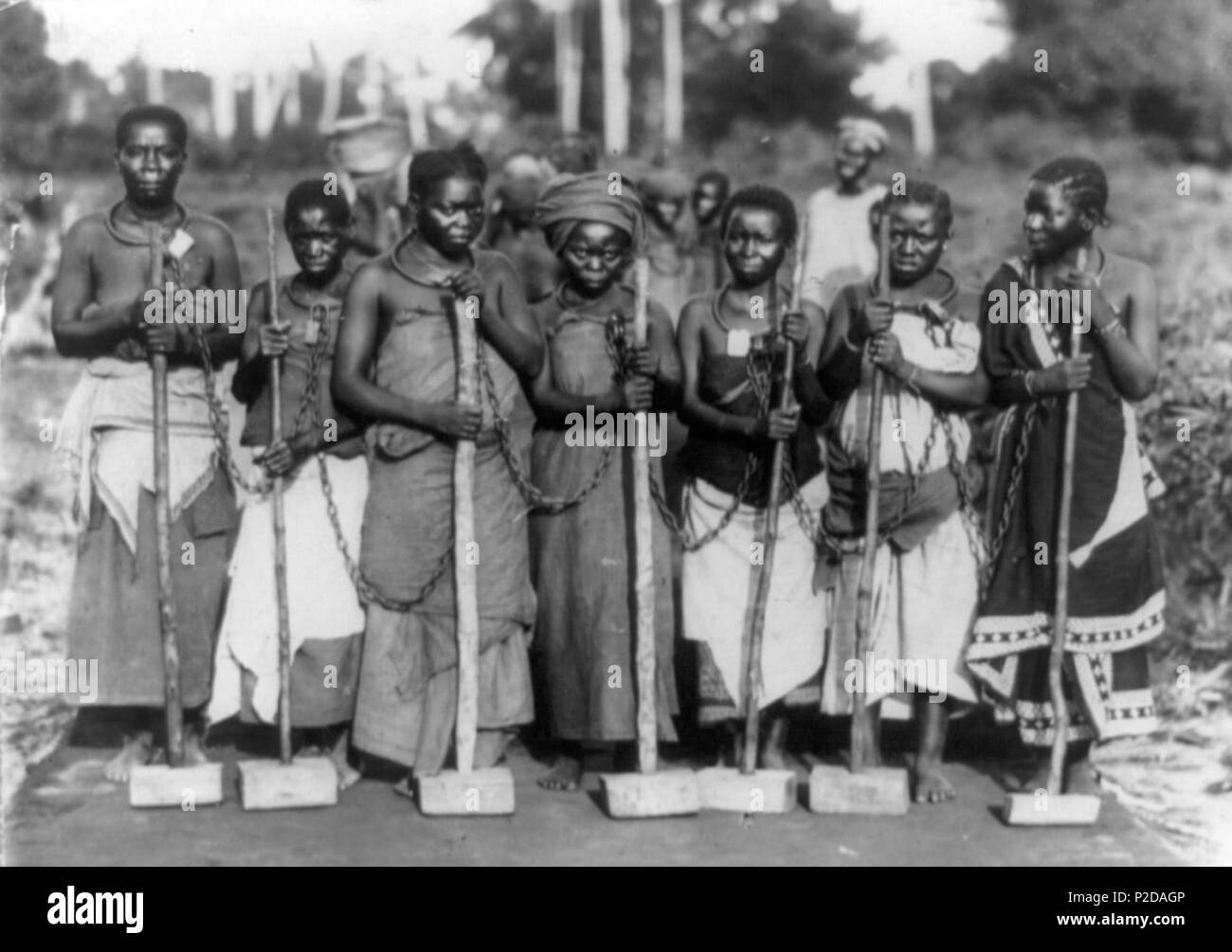 . Female convicts chained together by neck rings, working on a road in ...