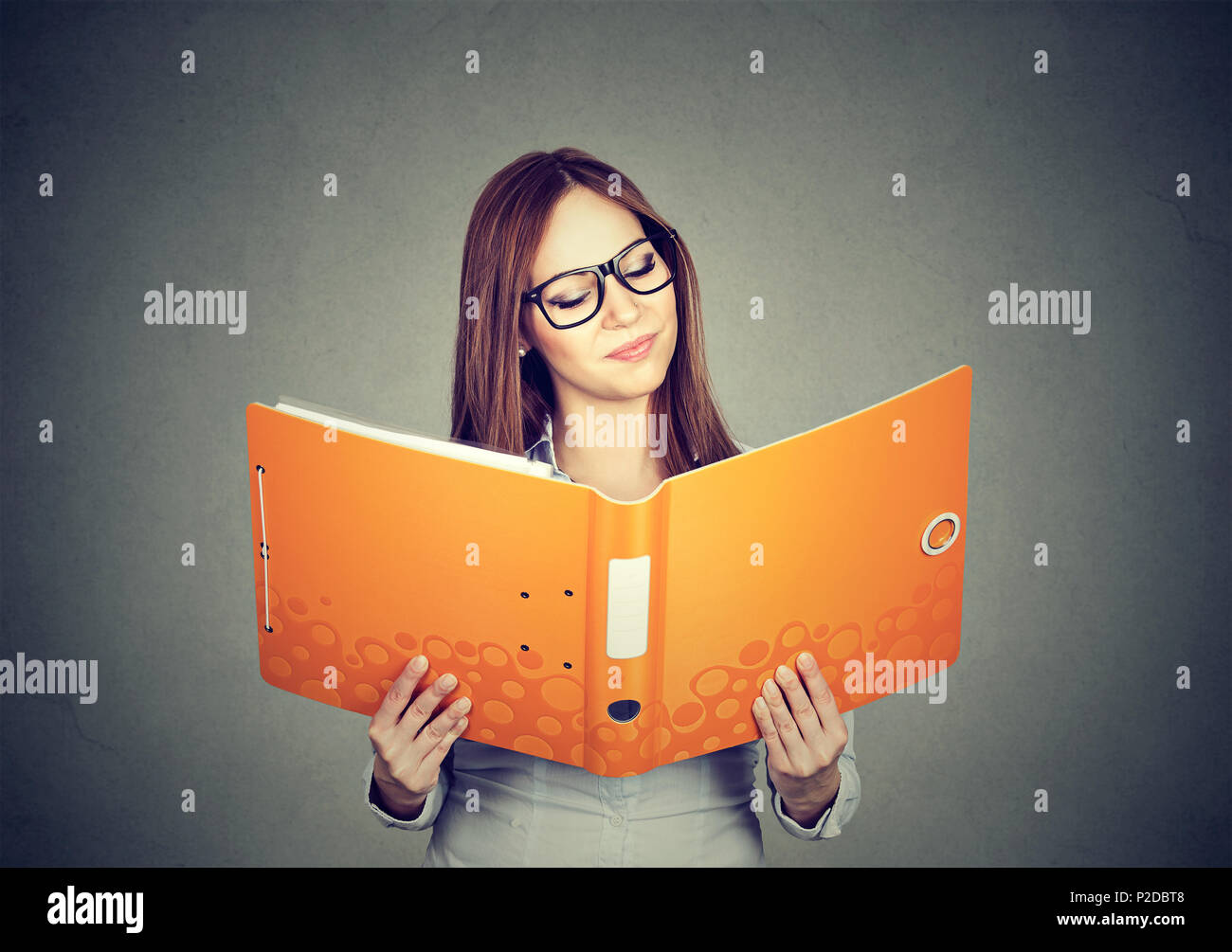 Young Woman In Glasses Excited With Education And Reading Huge Folder young-woman-in-glasses-excited-with-education-and-reading-huge-folder