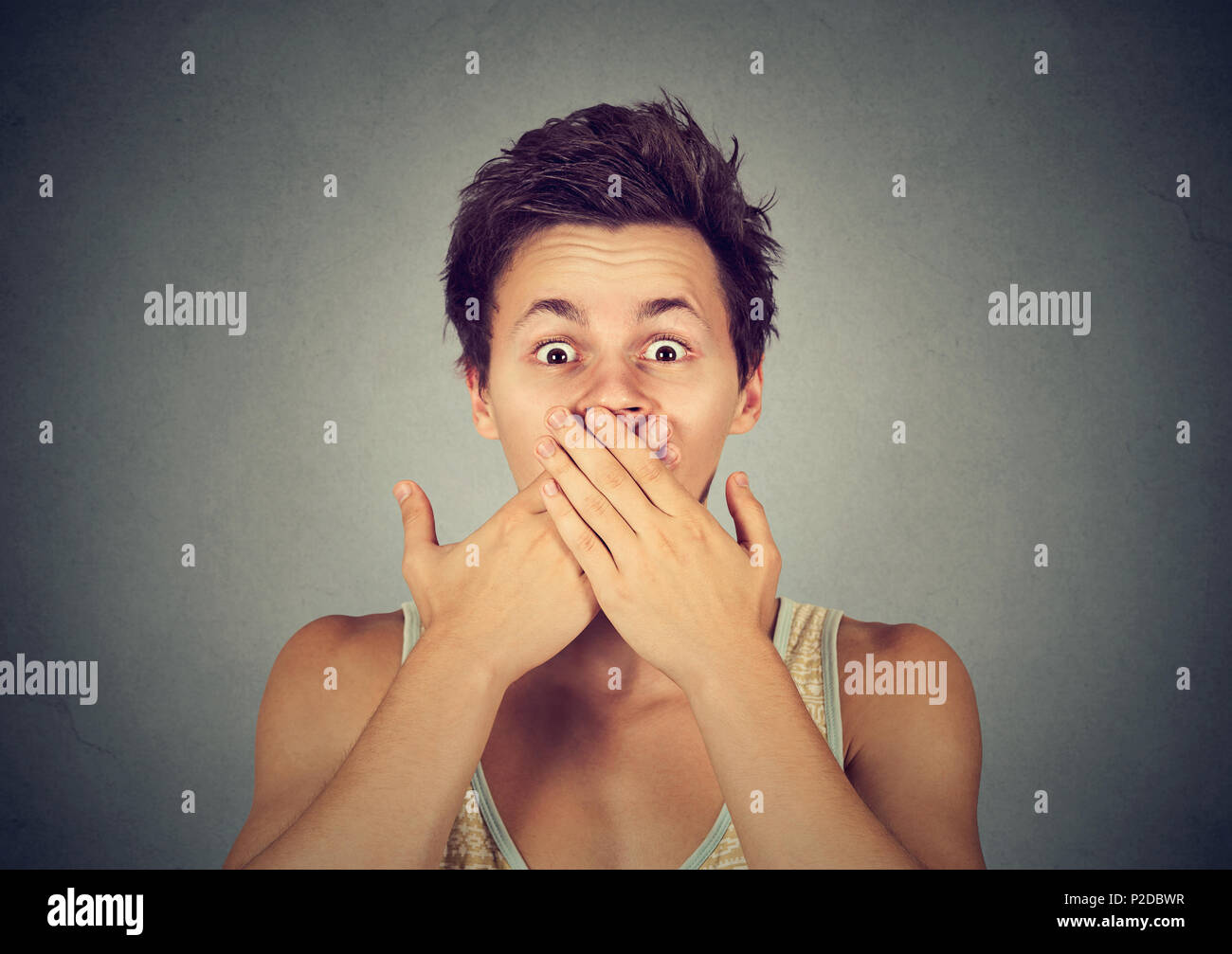 Young stunned guy covering mouth with both hands looking afraid of ...
