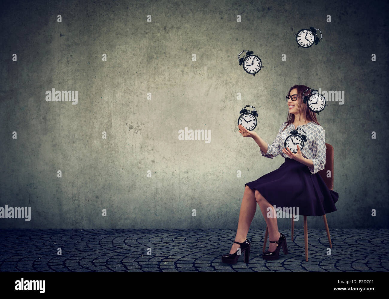 Happy skillful woman sitting on chair against gray concrete wall and ...