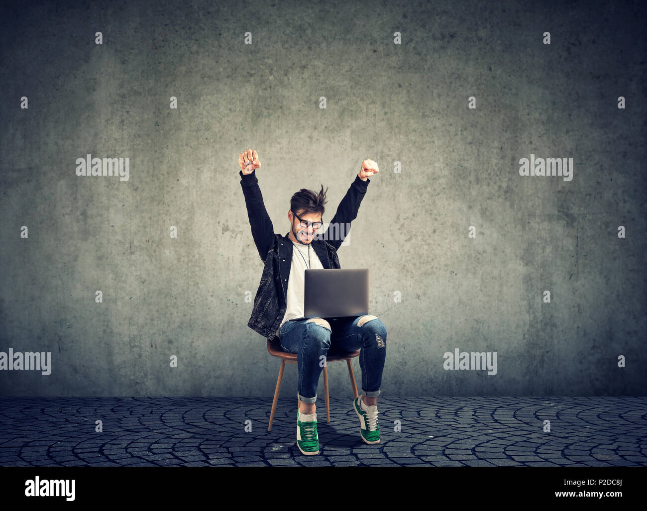 Stylish hipster man sitting on chair with laptop and celebrating ...