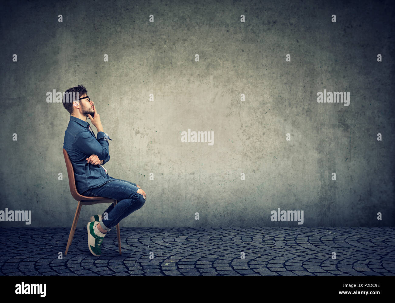 Side view of lonely mindful man sitting on chair and contemplating on ...