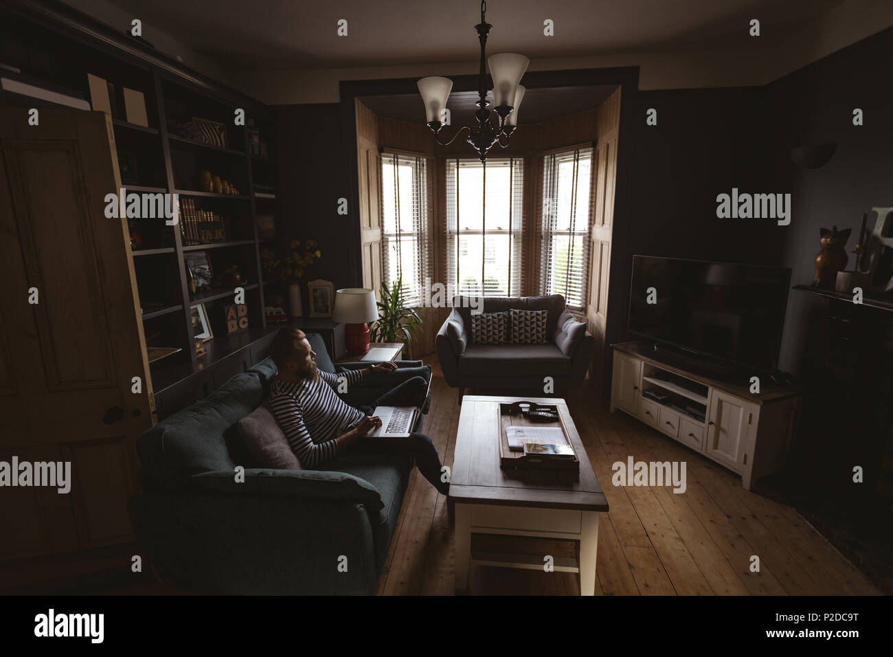 Man seating on sofa using his laptop Stock Photo - Alamy