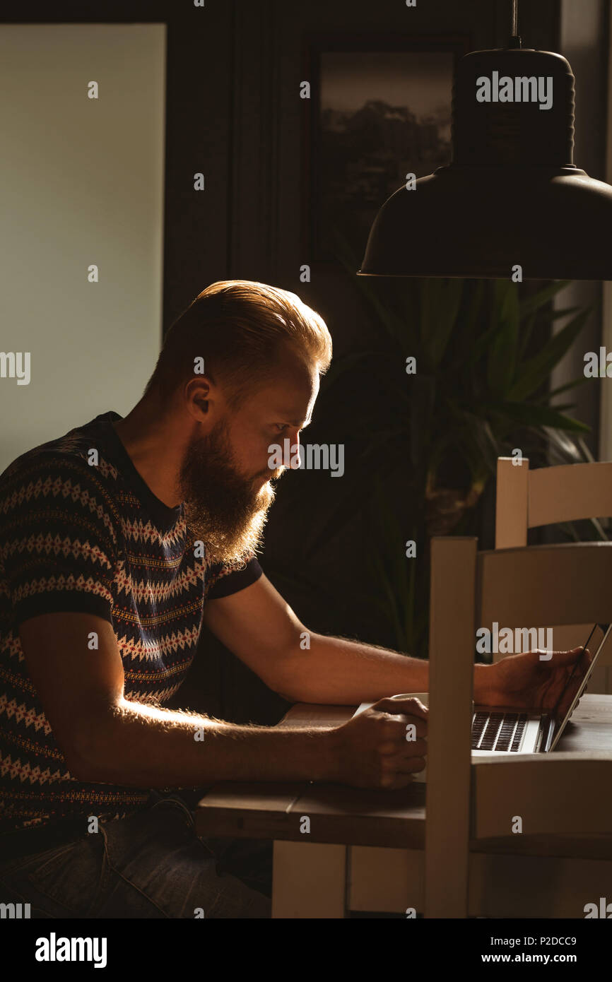 Man sitting on chair using his laptop at home Stock Photo - Alamy