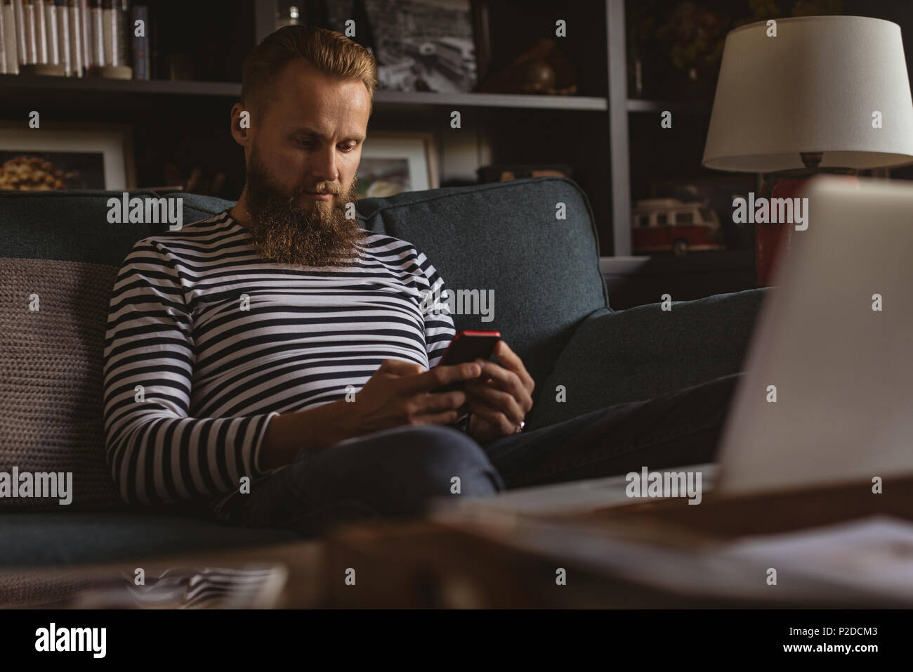Man sitting on sofa using his mobile phone Stock Photo - Alamy