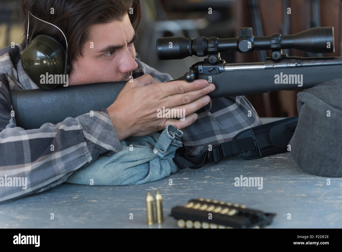 Man aiming sniper rifle at target in shooting range Stock Photo - Alamy
