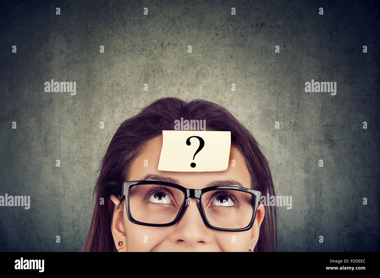 Young woman wearing black glasses with question mark on forehead ...