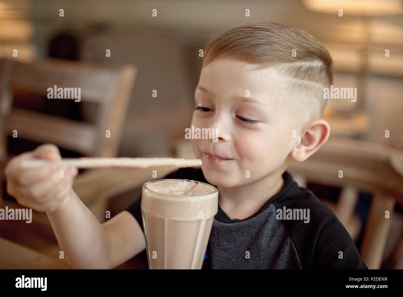 little boy drinking milkshake sitting at the table in cafe Stock Photo ...