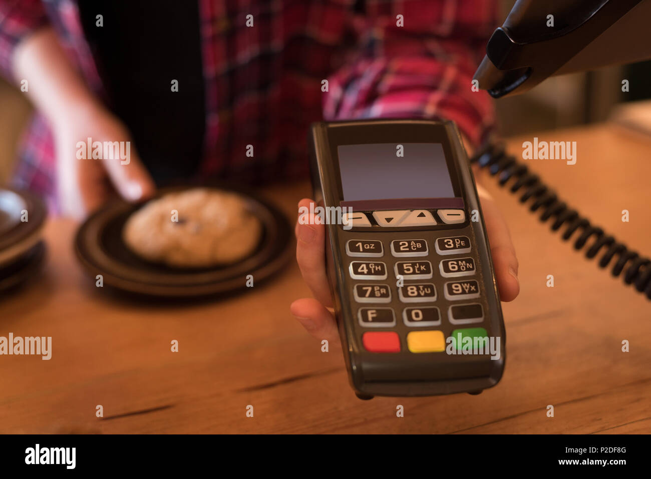 Mid section of woman holding payment terminal at counter Stock Photo ...