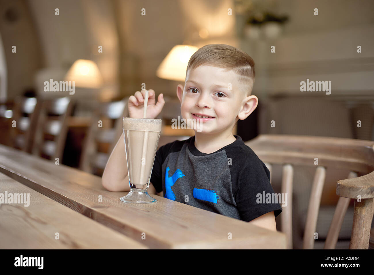 little boy drinking milkshake sitting at the table in cafe Stock Photo ...