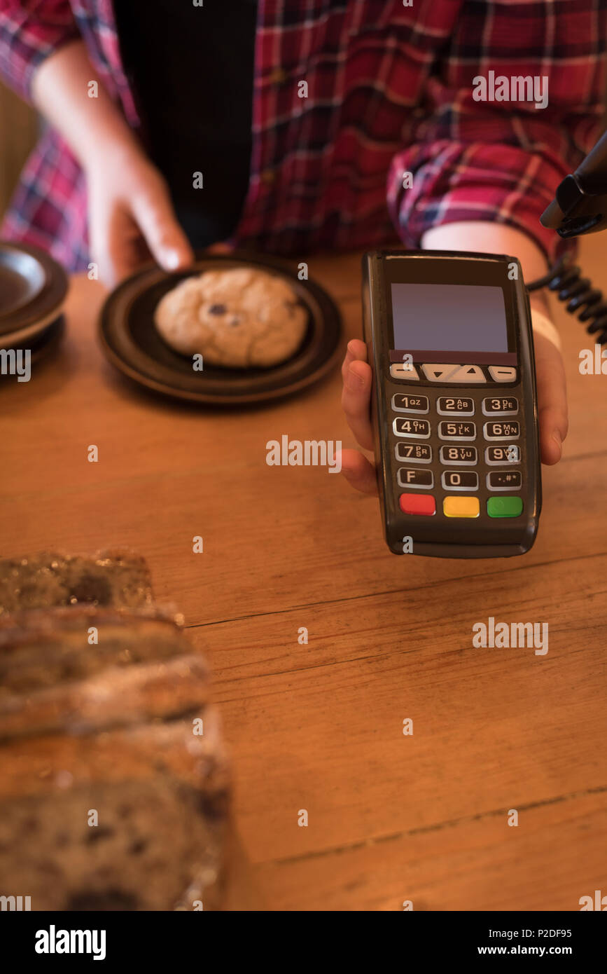 Mid section of woman holding payment terminal at counter Stock Photo ...