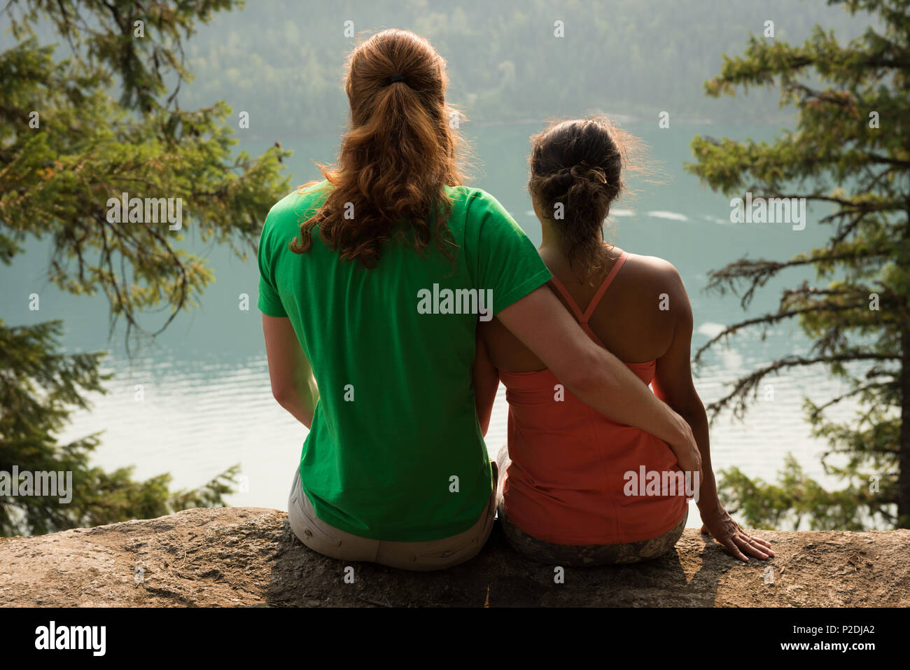 Sporty couple sitting near each other on the edge of a rock Stock Photo ...