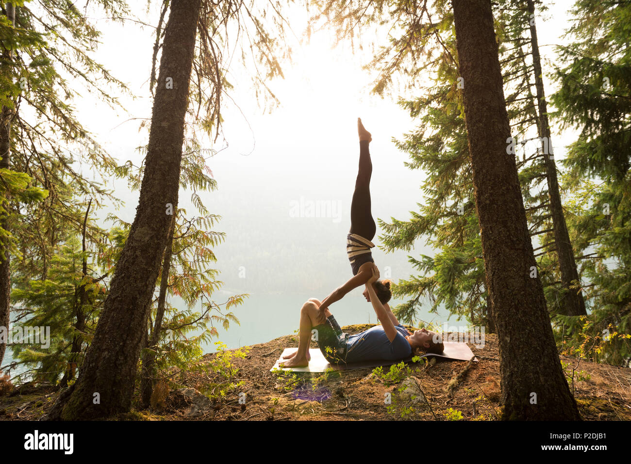 Sporty couple practicing acro yoga in a lush green forest Stock Photo ...