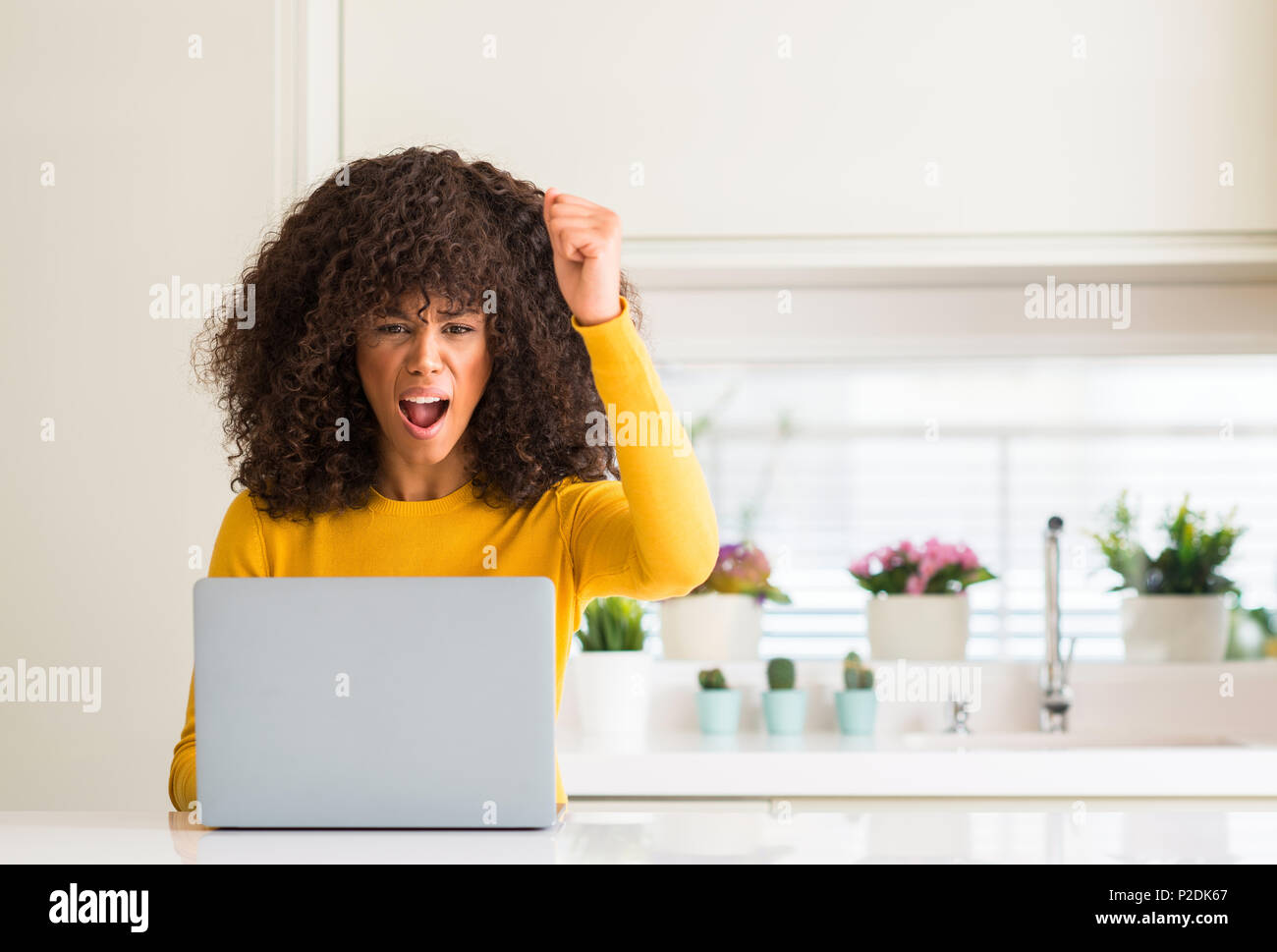 African american woman using computer laptop at kitchen annoyed and ...