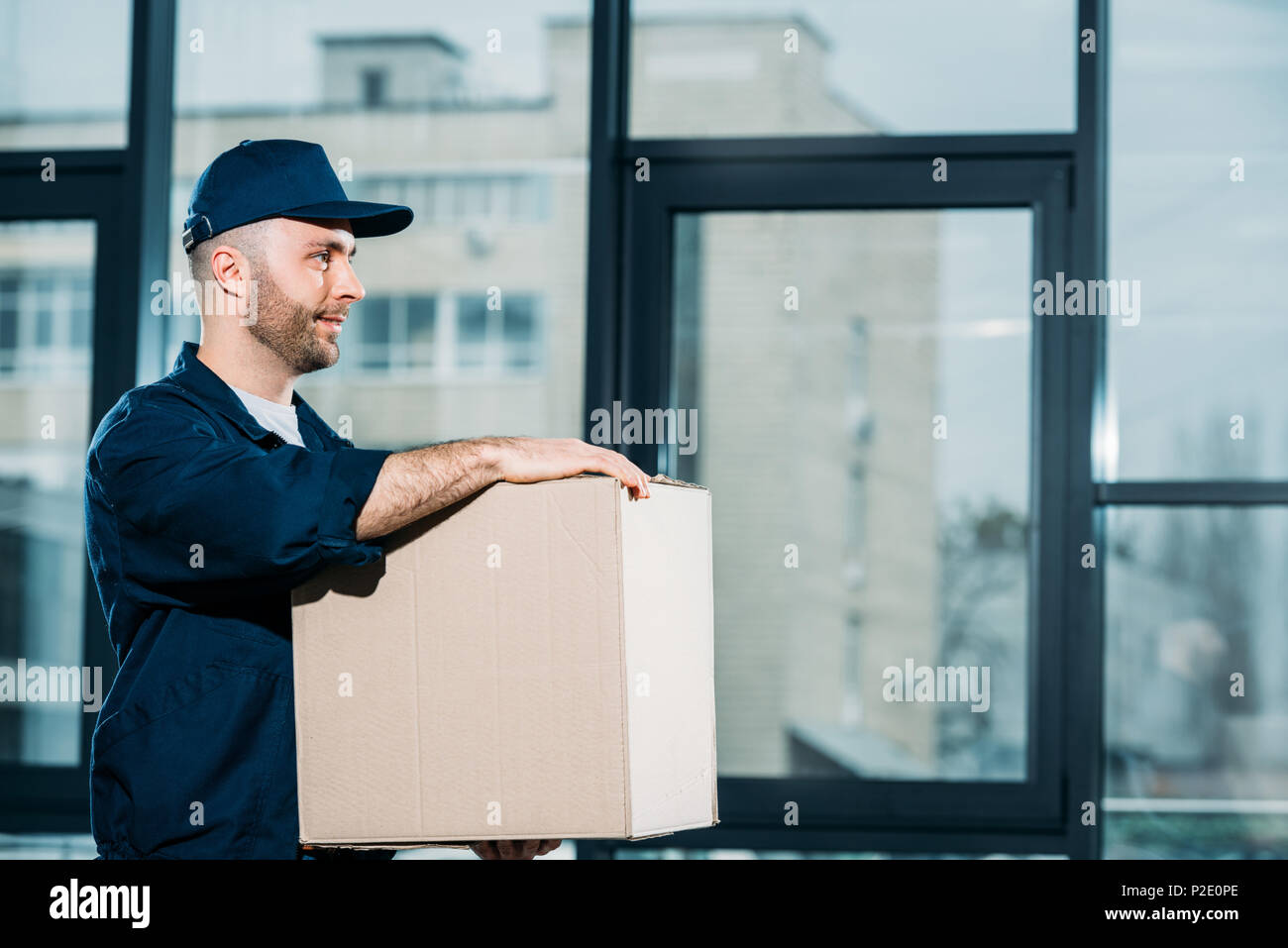 Young delivery man carrying cardboard box Stock Photo - Alamy