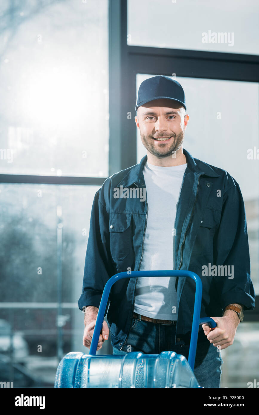 Loader holding delivery cart with water bottles Stock Photo - Alamy