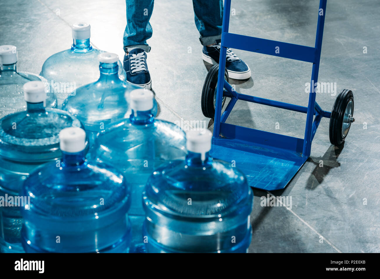 Loader man with delivery cart standing by water bottles Stock Photo - Alamy