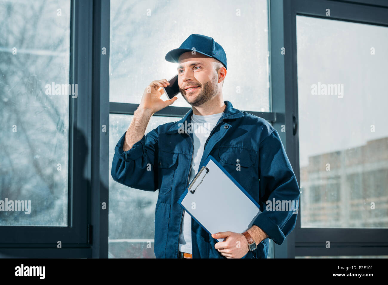 Courier holding clipboard and making a phone call Stock Photo - Alamy