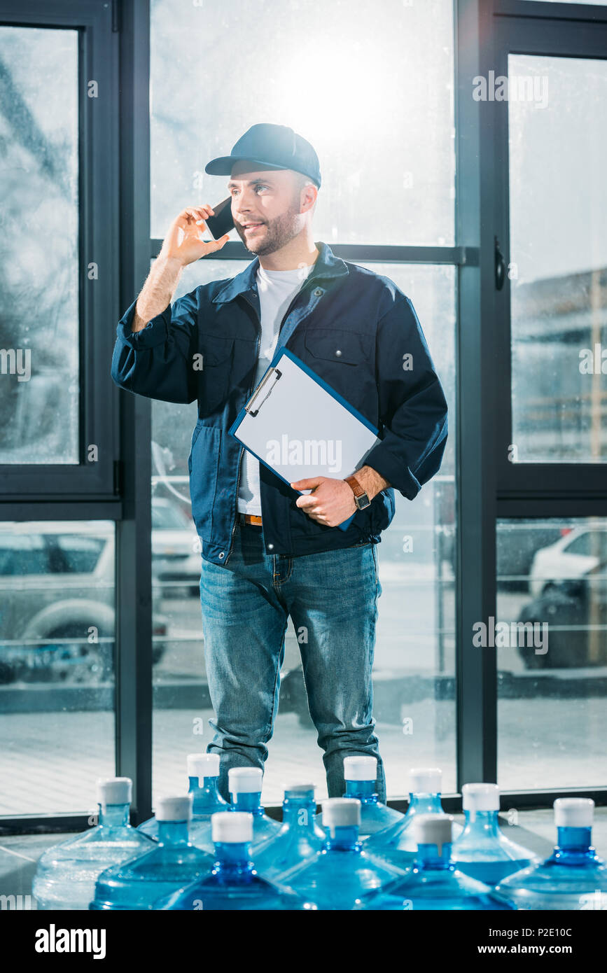 Delivery man with clipboard talking on a phone Stock Photo - Alamy