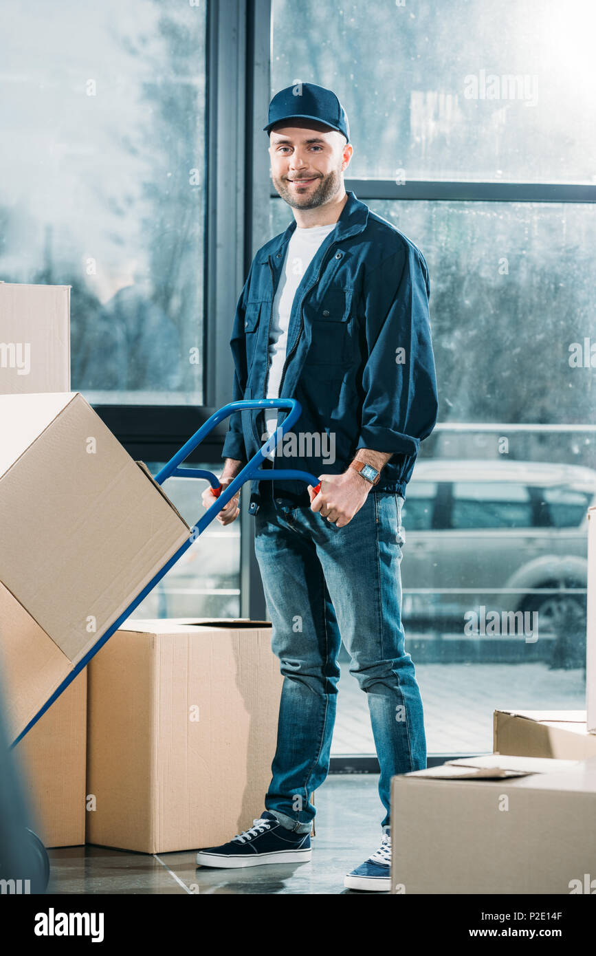 Delivery man pushing hand truck with boxes Stock Photo - Alamy