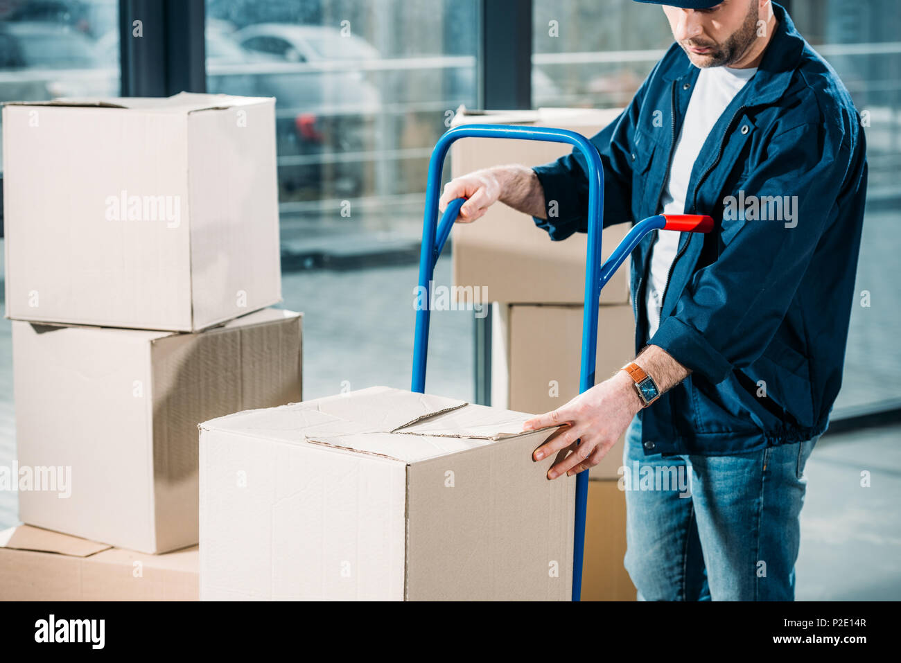 Loader man stacking cardboard boxes on hand truck Stock Photo - Alamy