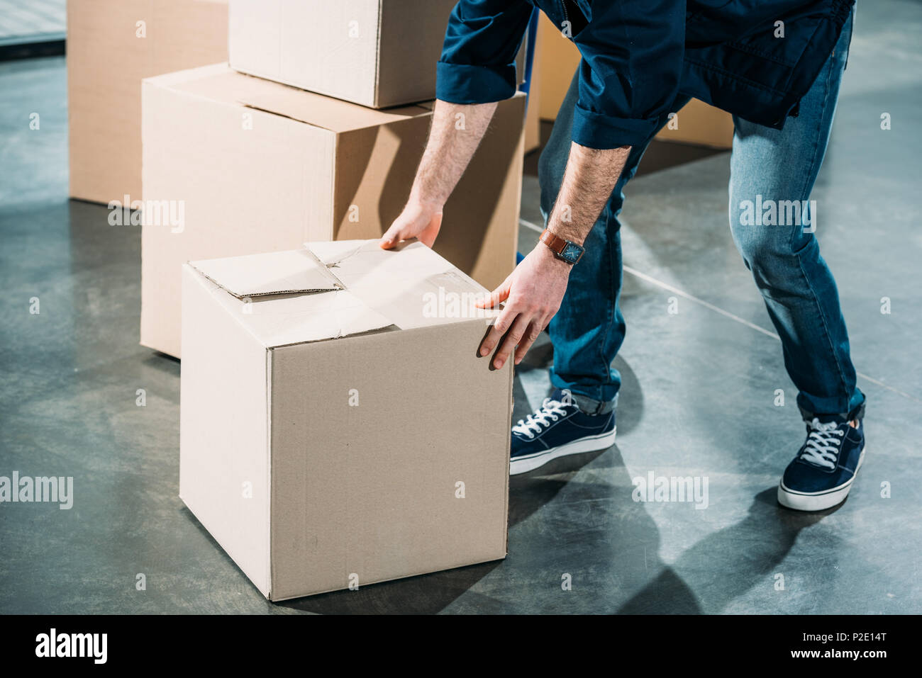 Loader man lifting cardboard box Stock Photo - Alamy