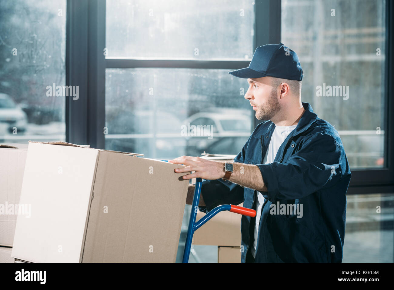 Loader man adjusting cardboard boxes on cart Stock Photo - Alamy
