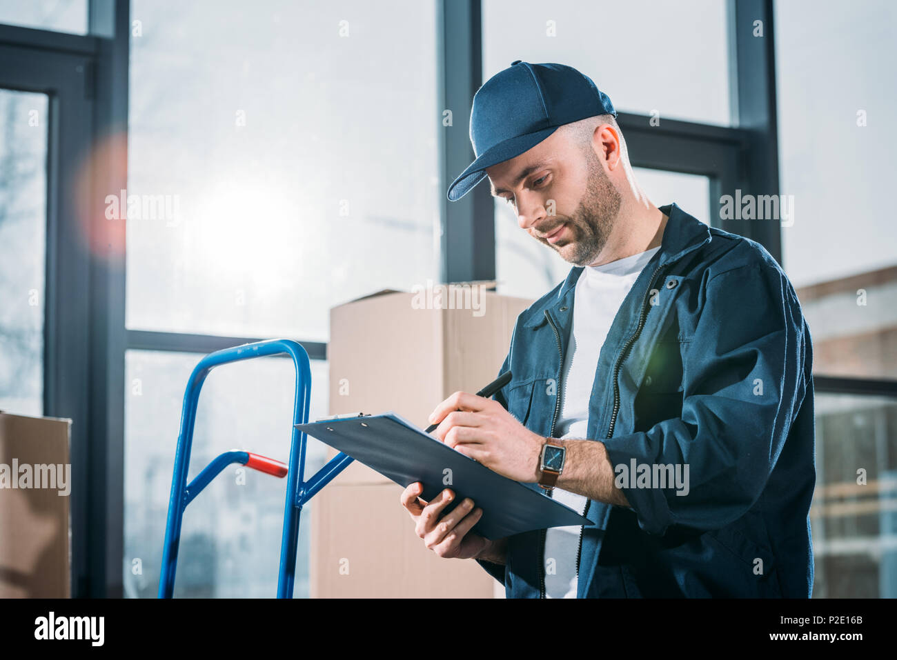 Loader man filling cargo declaration by stacks boxes Stock Photo - Alamy