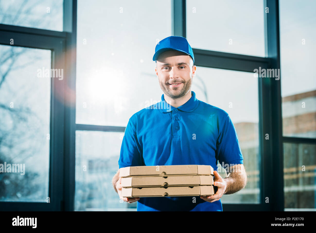 Smiling delivery man carrying pizzas in boxes Stock Photo - Alamy