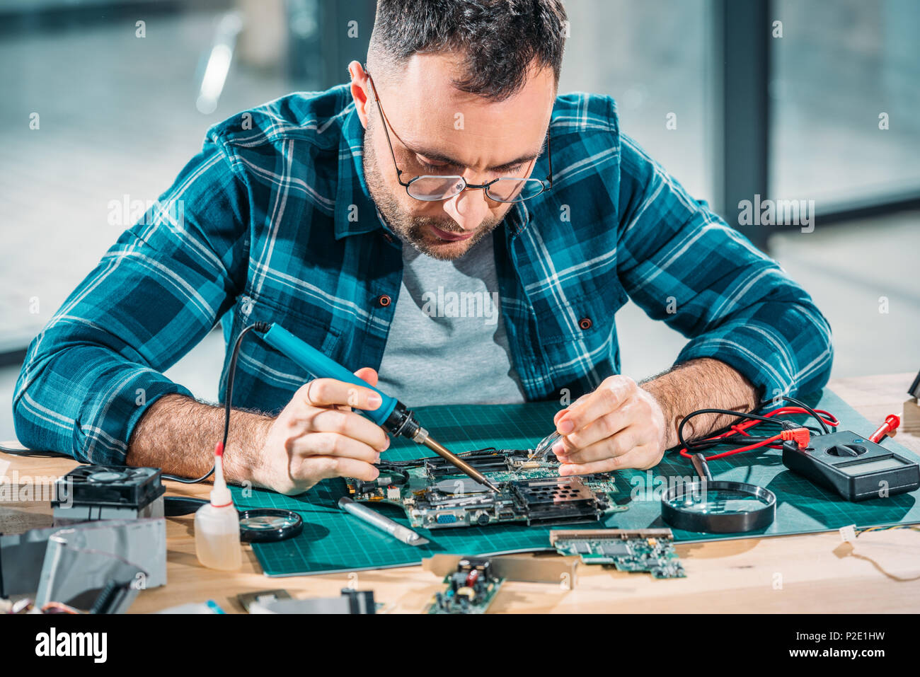 Hardware engineer in glasses soldering pc parts Stock Photo - Alamy