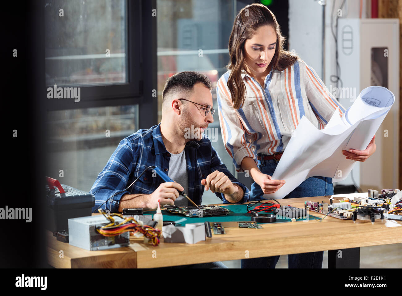 Woman and man engineers looking at hardware blueprint Stock Photo - Alamy