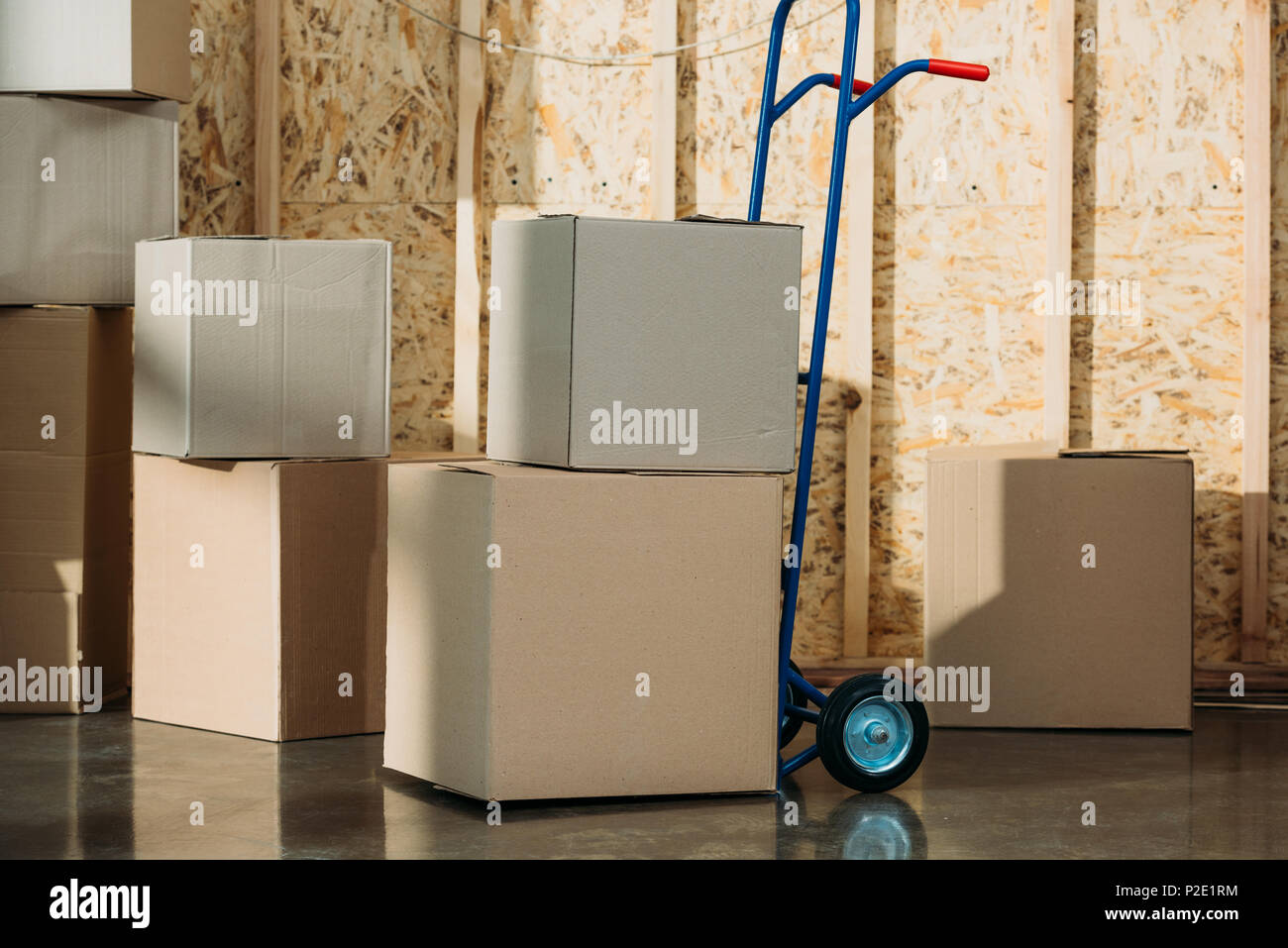Cardboard packages and delivery cart in warehouse room Stock Photo - Alamy