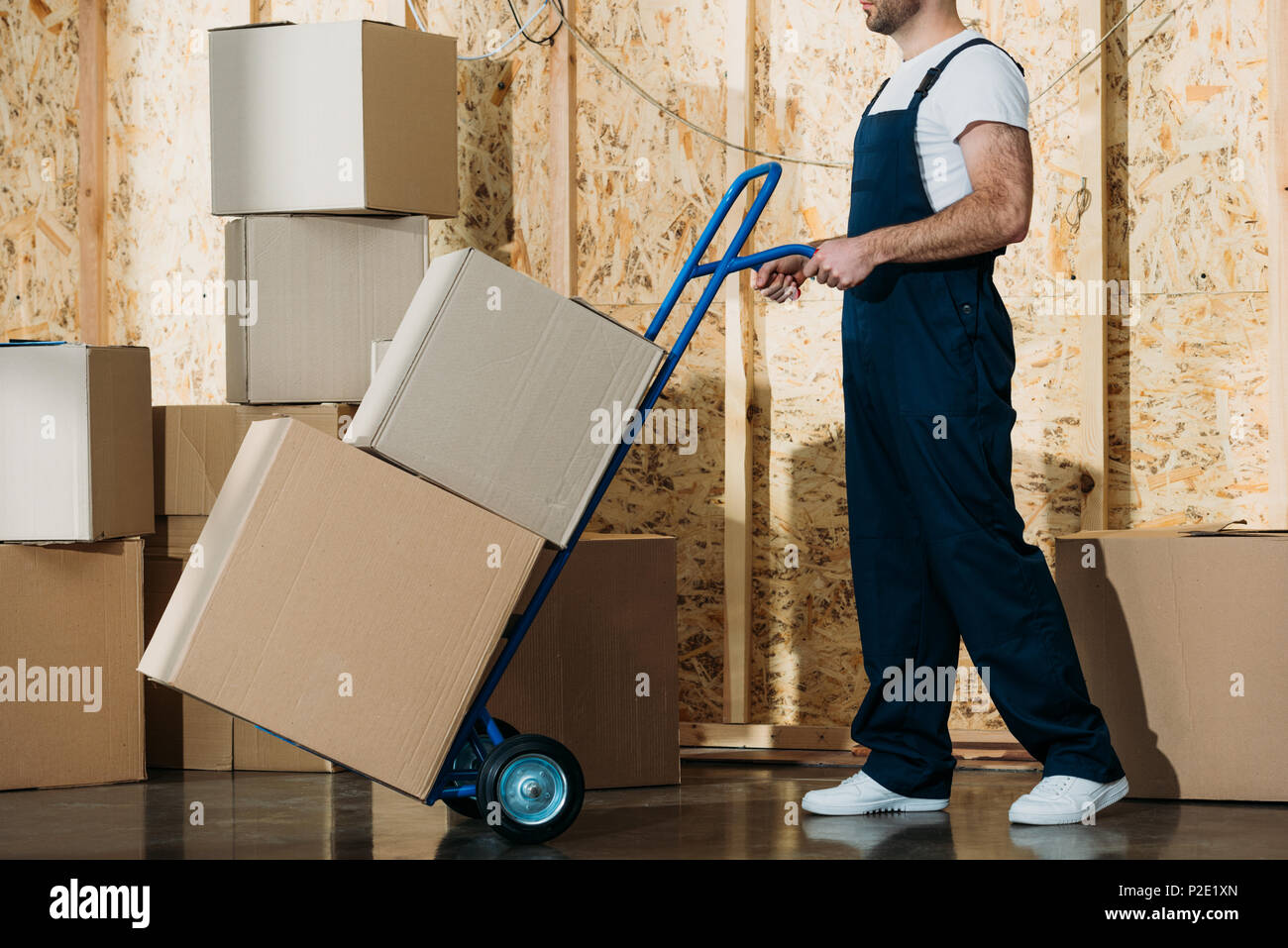 Delivery man carrying boxes on hand truck Stock Photo - Alamy