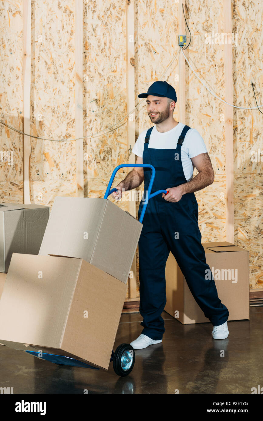 Loader man carrying cardboard boxes on hand truck Stock Photo - Alamy