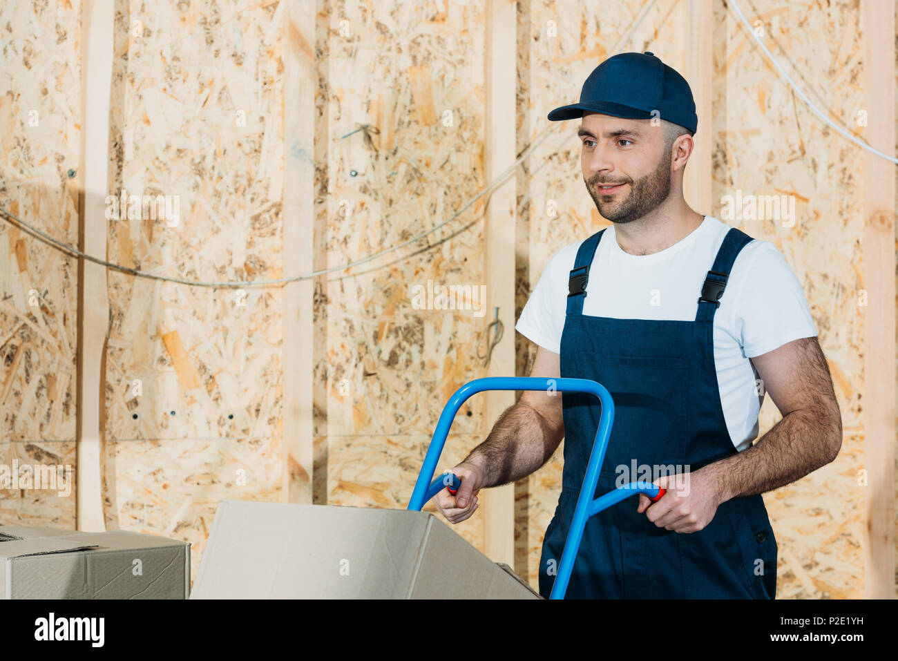 Delivery man pushing hand truck with boxes Stock Photo - Alamy