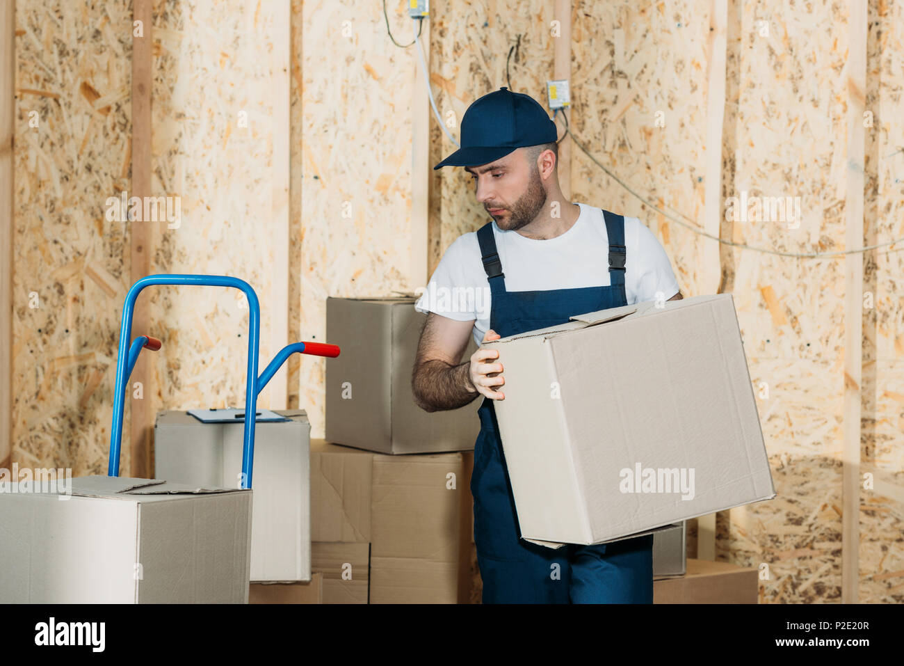 Loader man stacking cardboard boxes on hand truck Stock Photo - Alamy