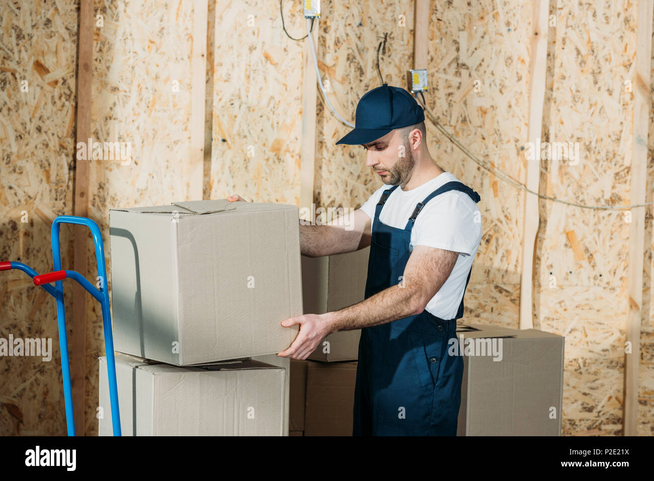 Delivery man stacking boxes on cart Stock Photo - Alamy