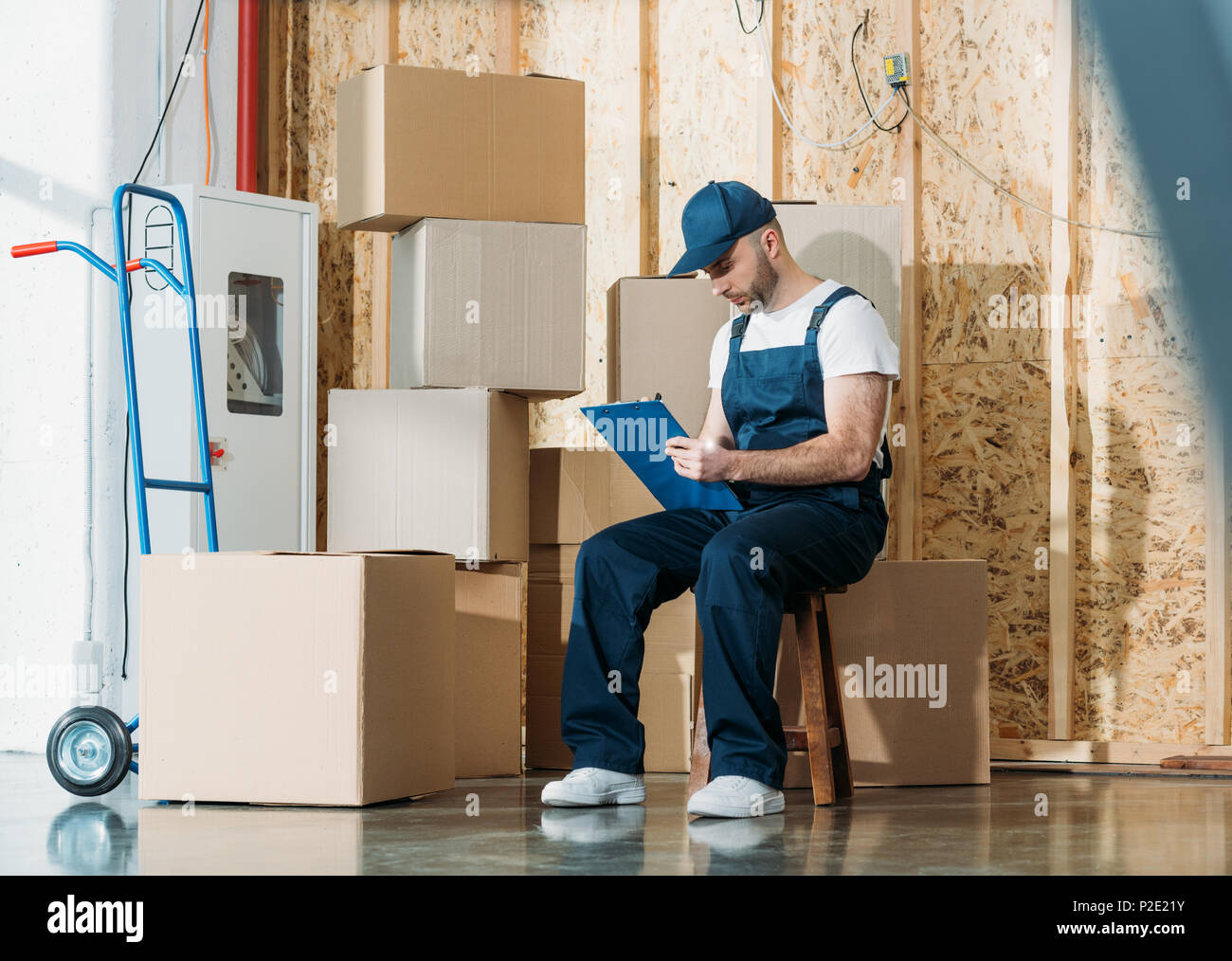 Loader man filling cargo declaration by stacks boxes Stock Photo - Alamy