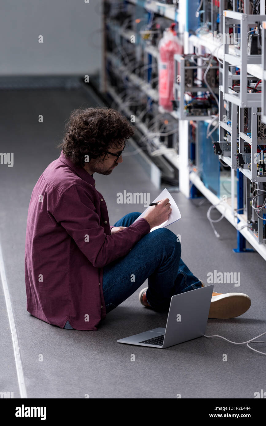 computer engineer working while sitting on floor at cryptocurrency ...