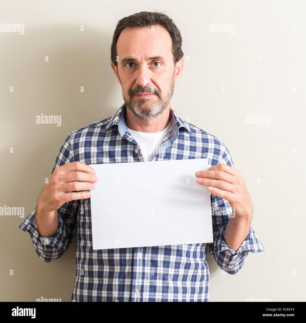 Senior man holding blank paper sheet with a confident expression on ...