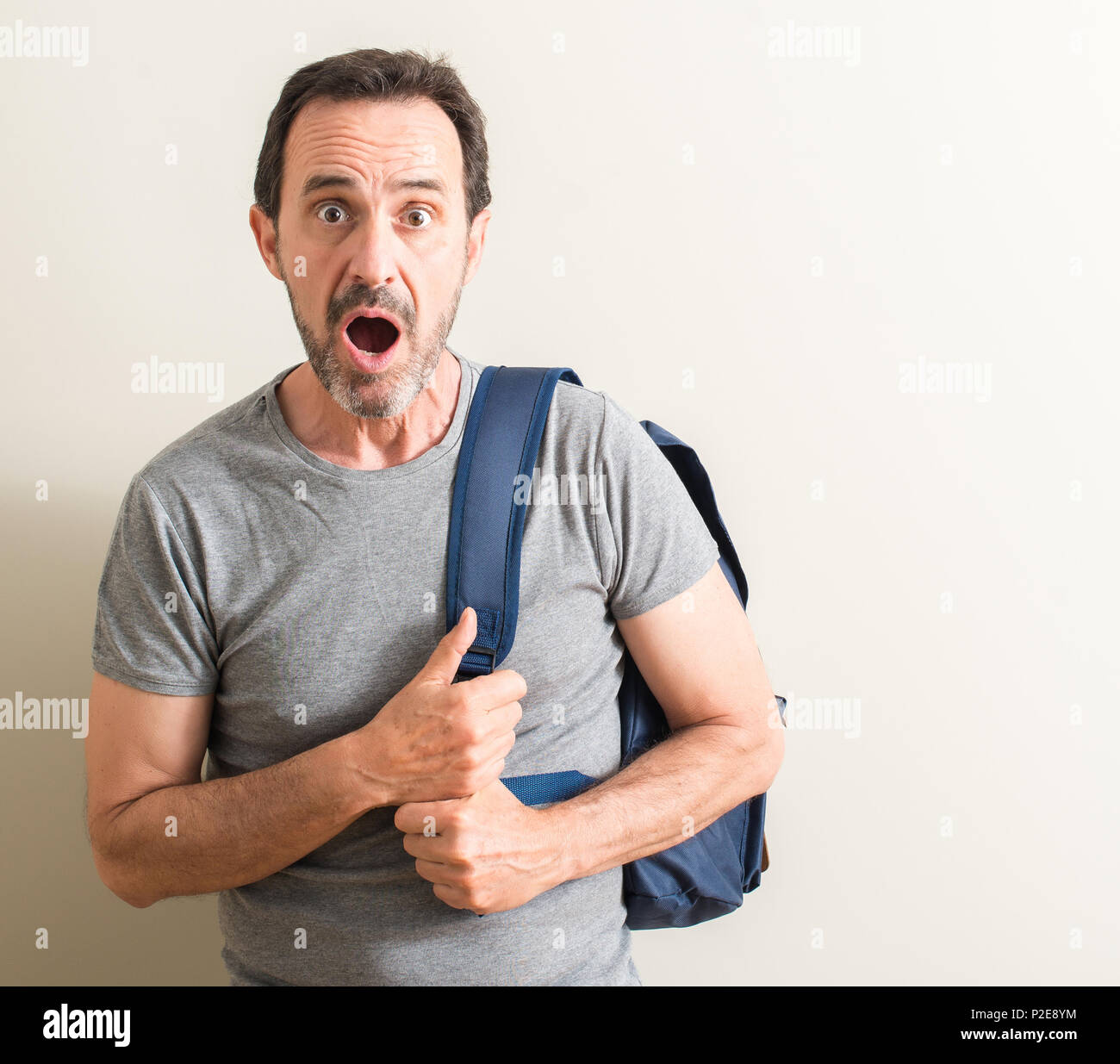 Senior man using backpack scared in shock with a surprise face, afraid ...