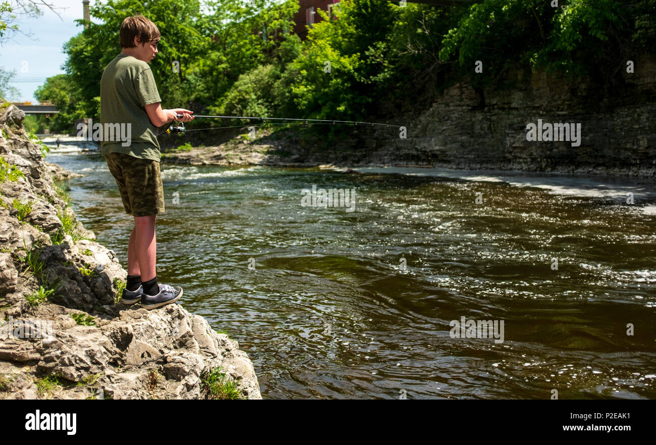 A man fishes in the Grand River as it runs through the town of Fergus ...