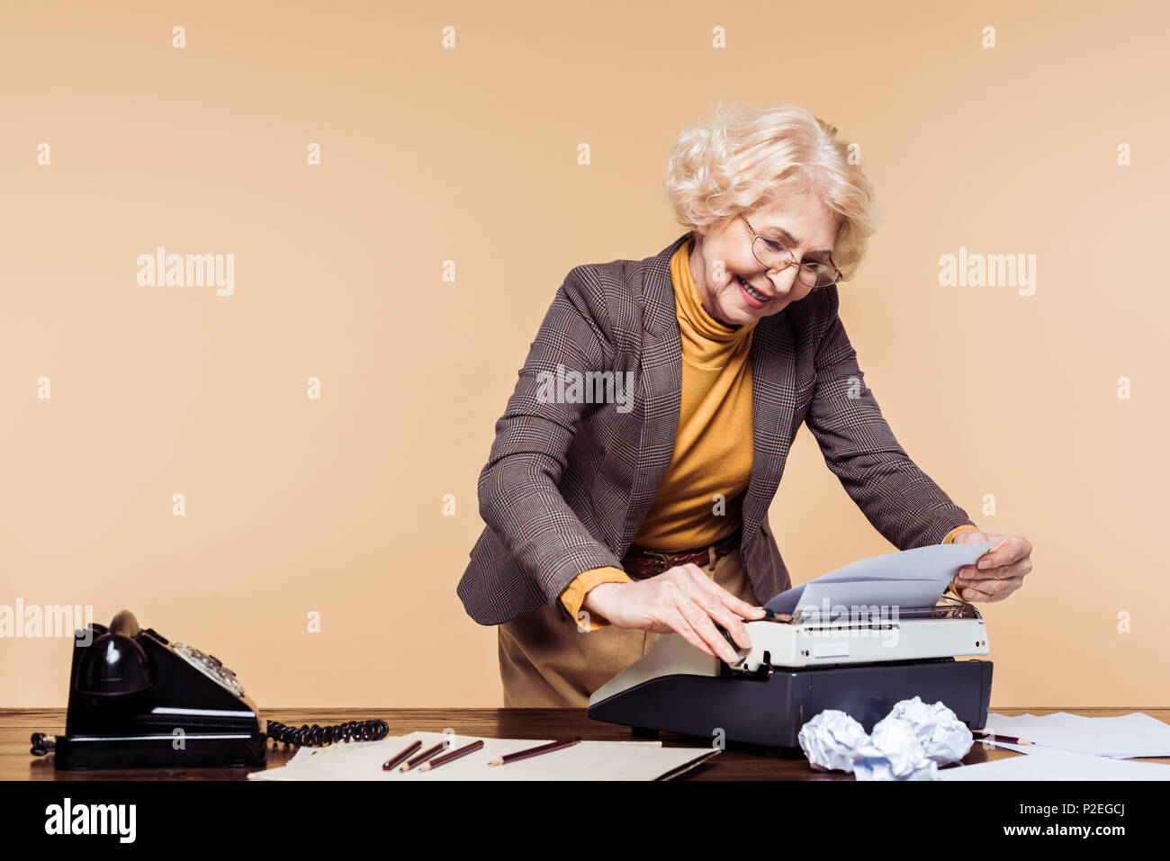 smiling senior woman using typewriter at table with rotary phone Stock ...