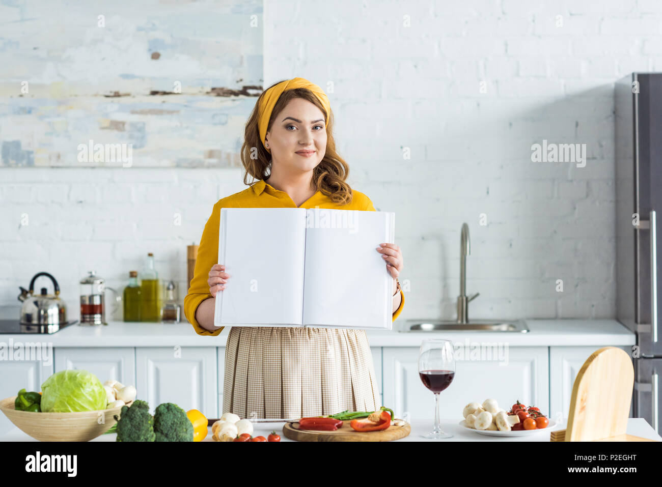beautiful woman showing recipe book in kitchen Stock Photo - Alamy