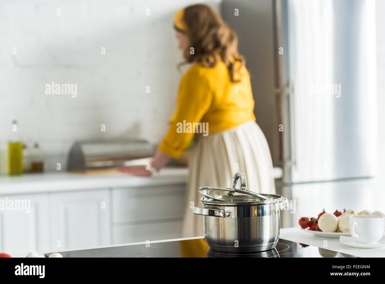woman cooking in kitchen with pan on electric stove on foreground Stock ...