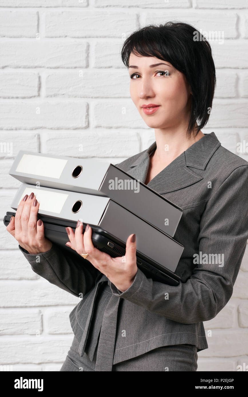 business woman with folder, dressed in a gray suit poses in front of a ...