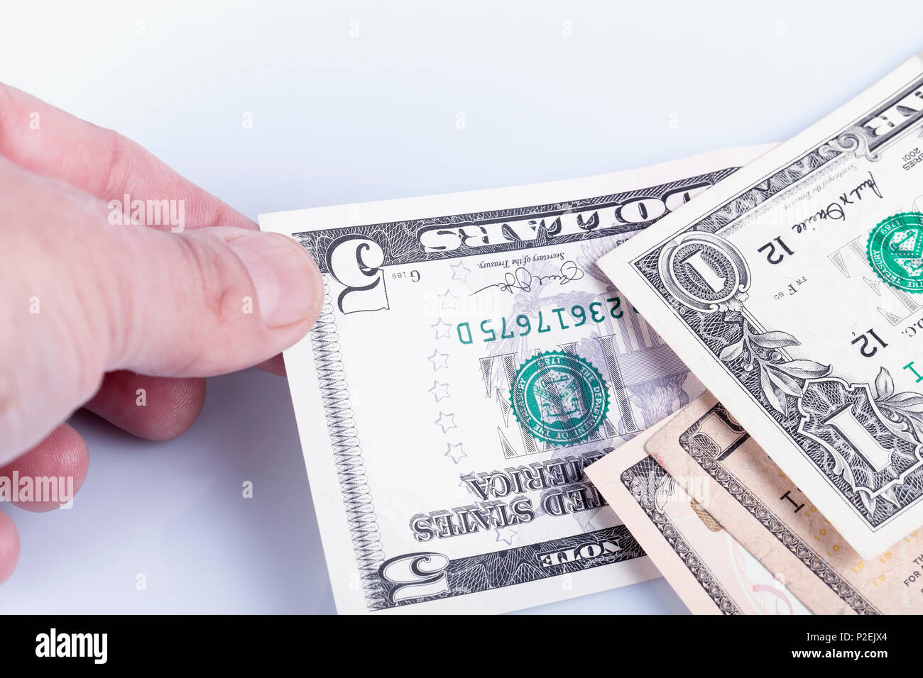 A man picks up a five dollar bill from between a pile and isolated on ...
